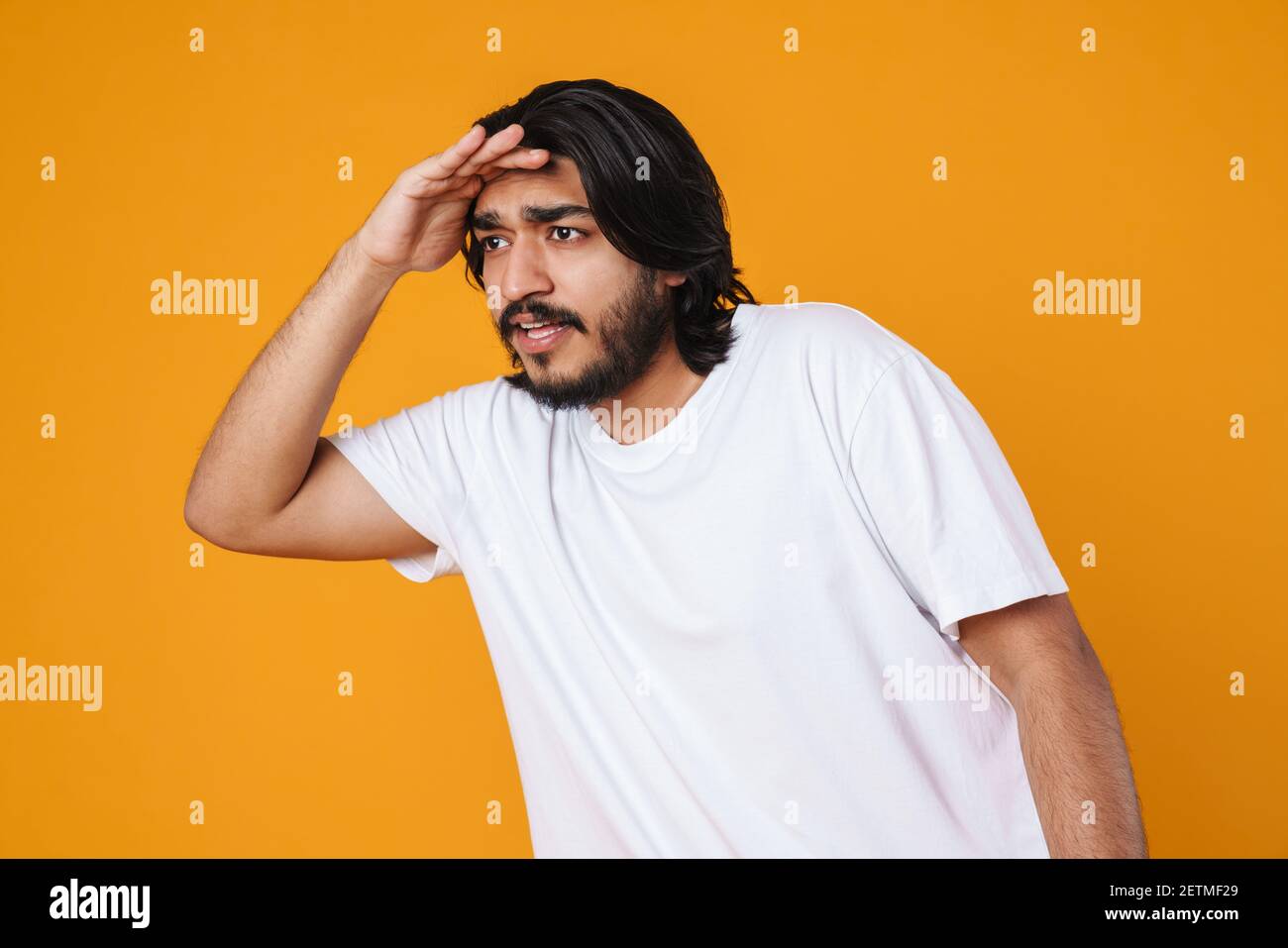 Upset young indian man looking far away with hand over head. Searching ...