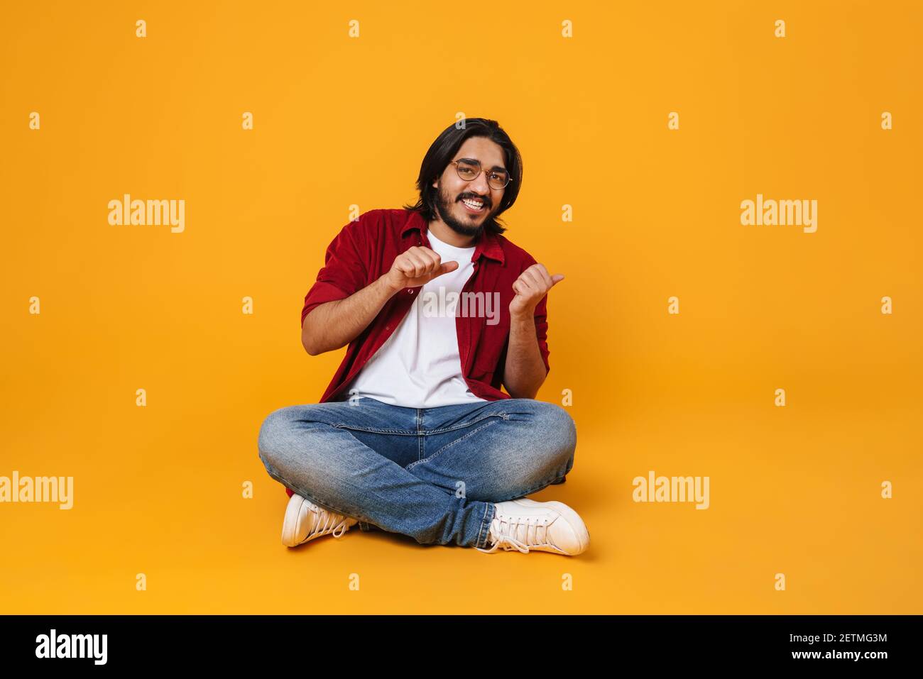Attractive young indian man presenting copy space isolated on yellow ...