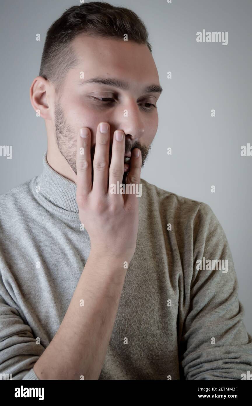 Portrait of a young man with a short beard with his hand on his cheek ...