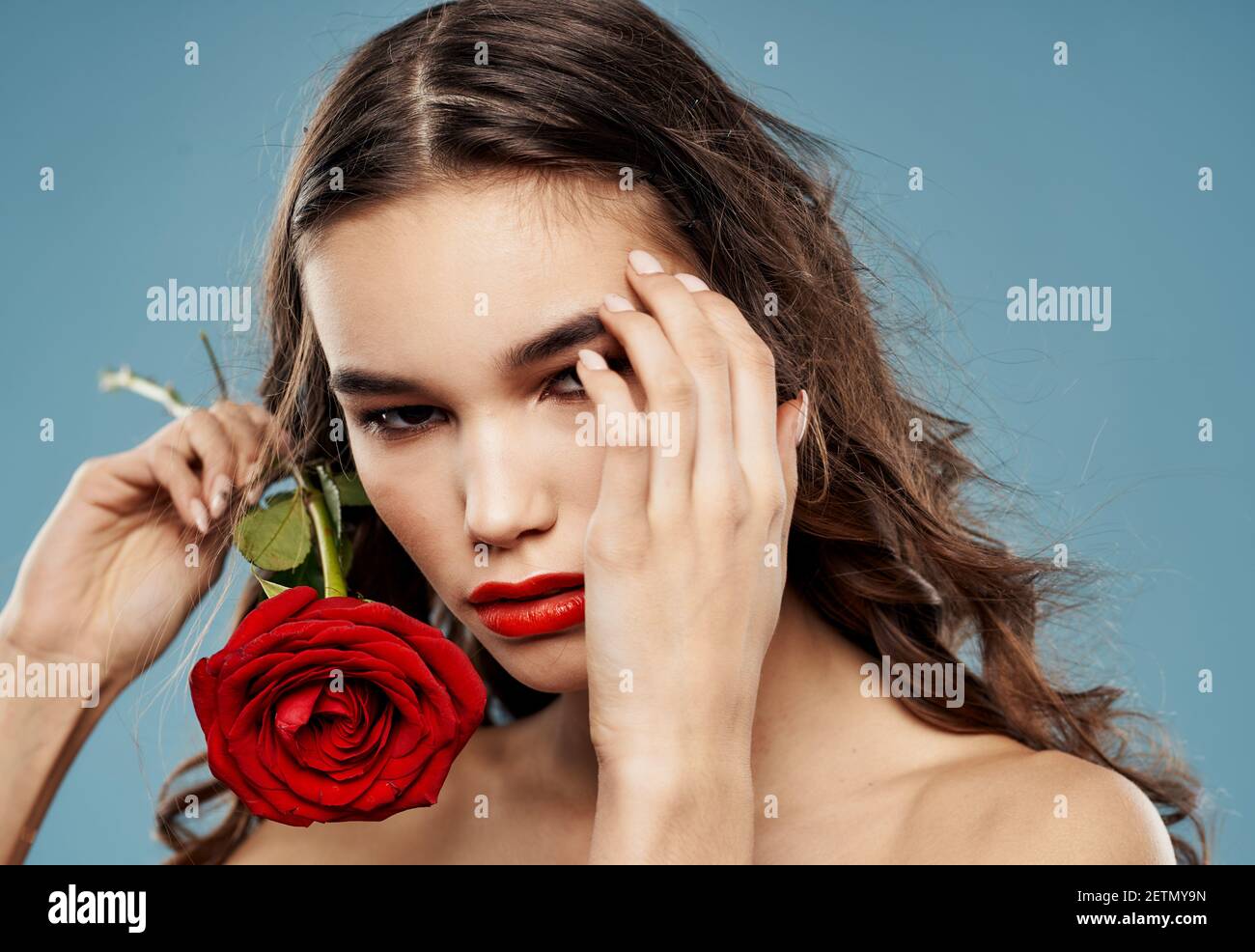Passionate woman with red rose eye shadow on eyelids blue background ...