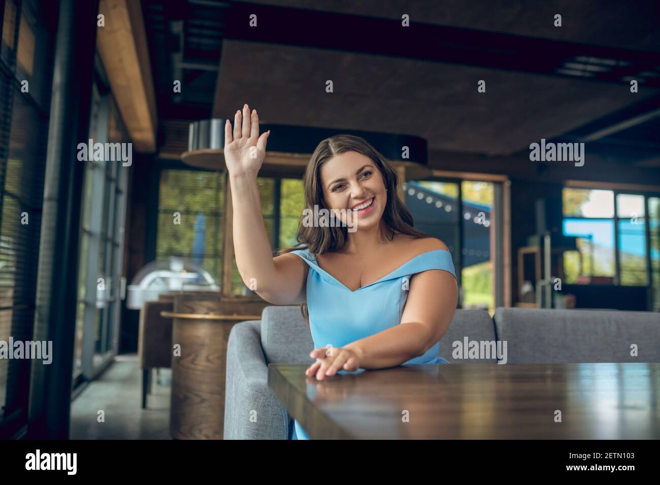 Emotional woman with raised hand as sign of greeting Stock Photo - Alamy