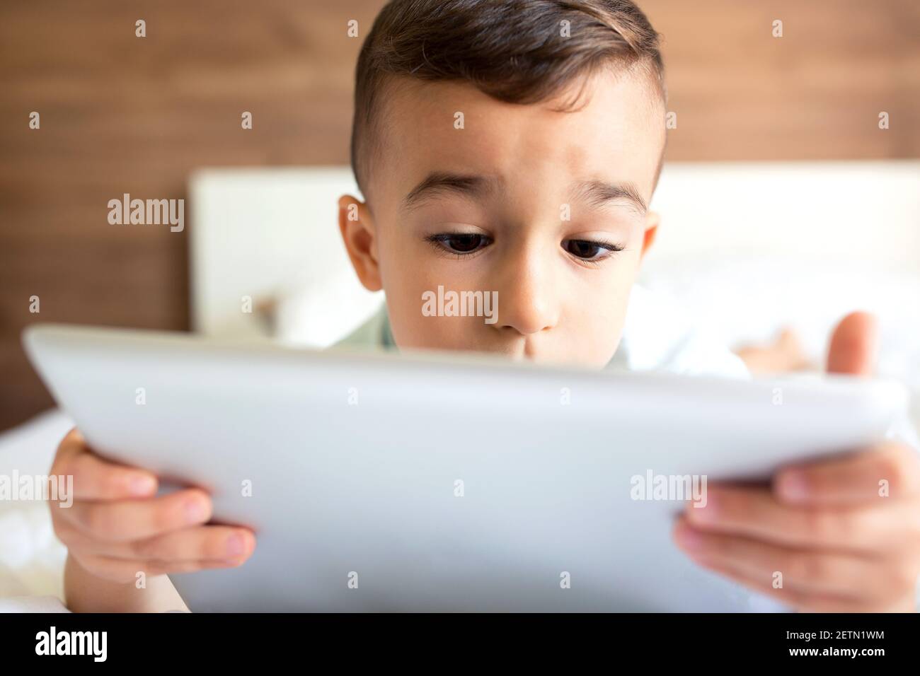 Cute little boy using his tablet and playing video games Stock Photo ...