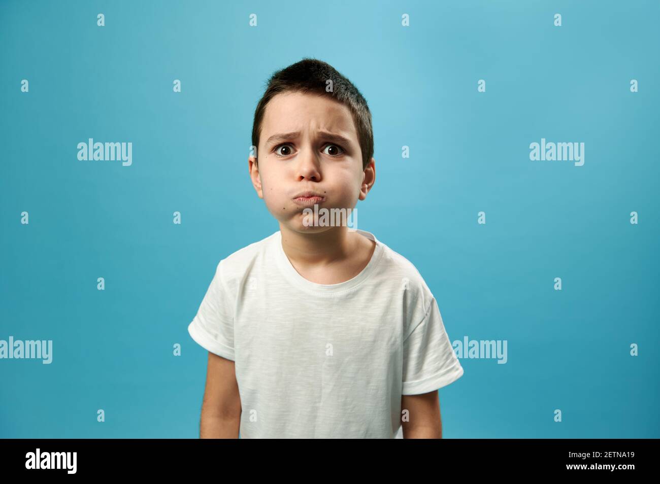 Boy in white t-shirt puffed out his cheeks. Facial emotions. Blue ...