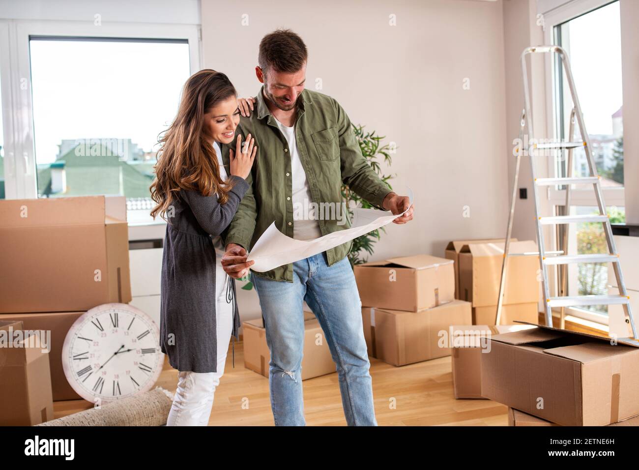 Two lovebirds holding a plan of their new home while making a break from unpacking Stock Photo ...