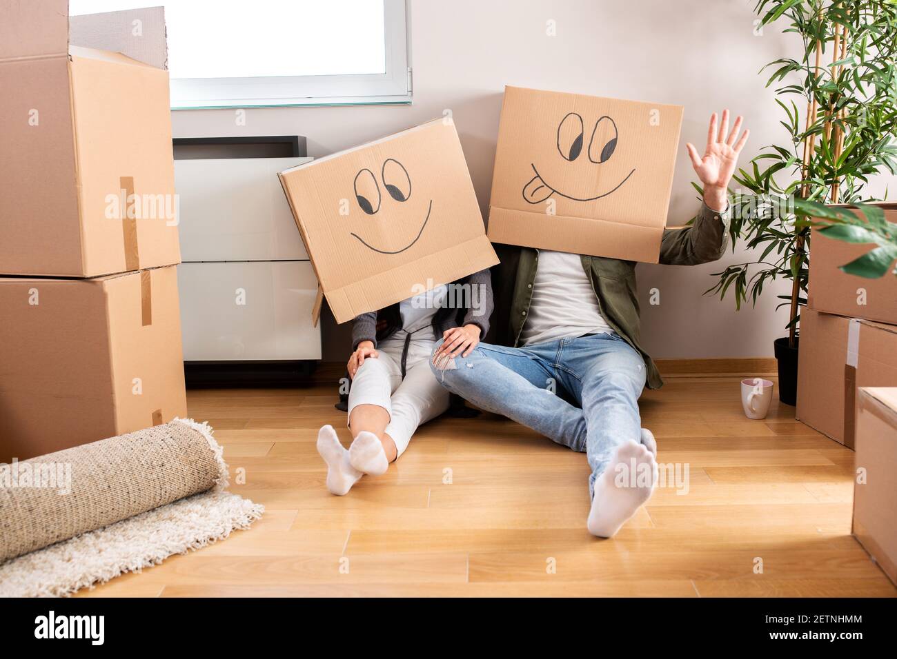 Love birds moving in a new home with boxes on their heads sitting on ...