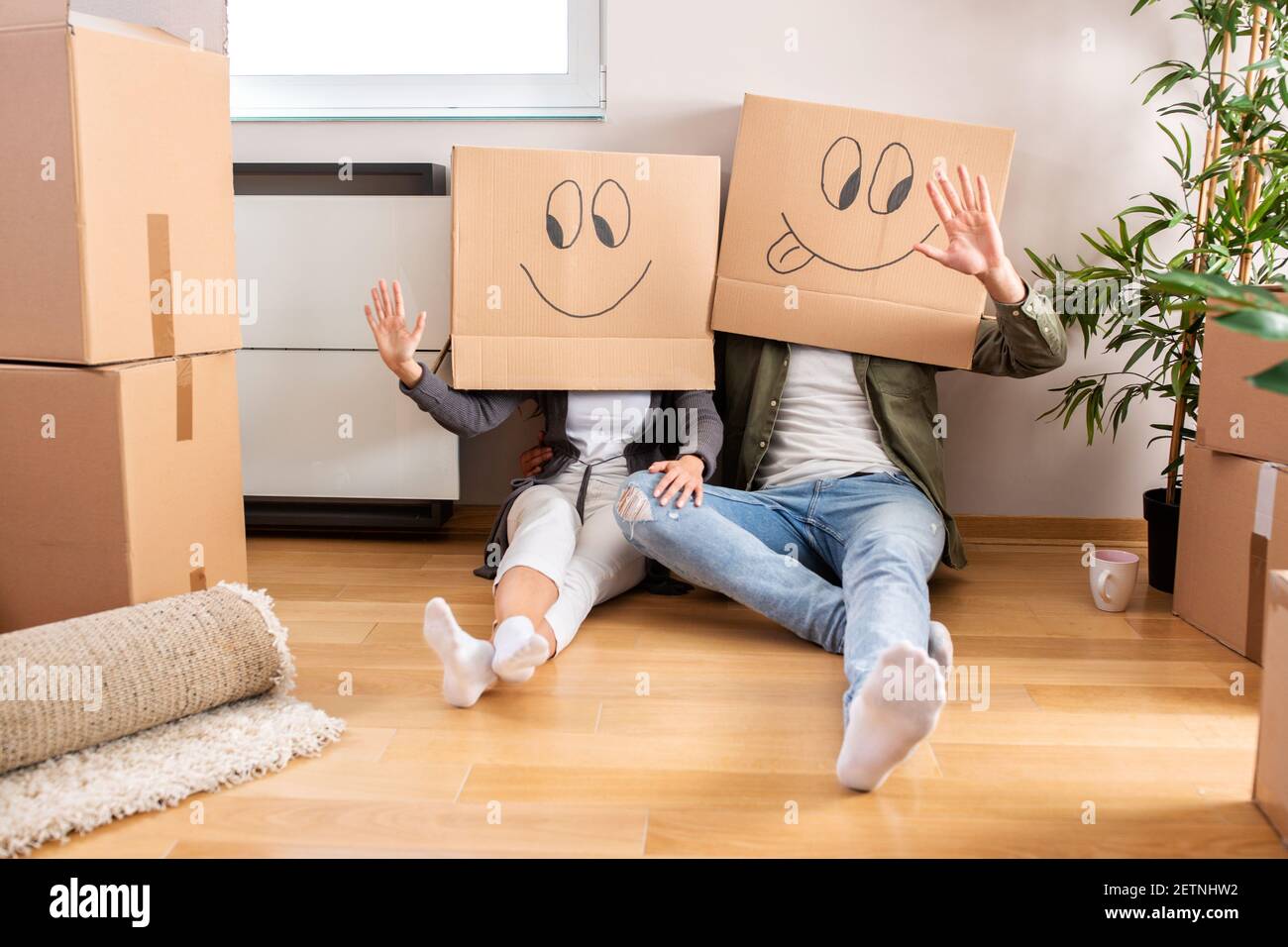 Love birds moving in a new home with boxes on their heads sitting on ...