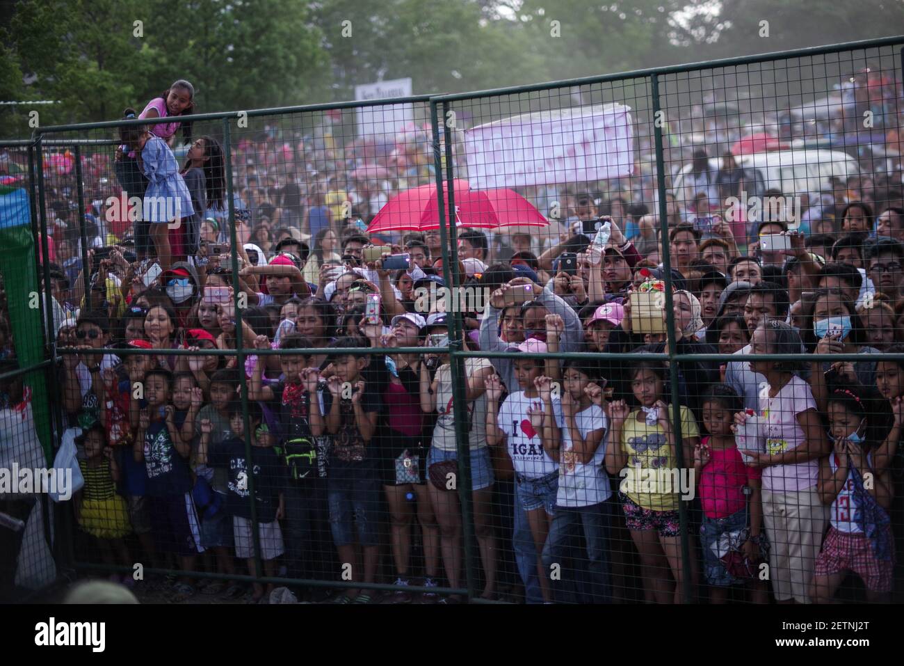 Several hundreds of spectators packed against a fence as they witness ...