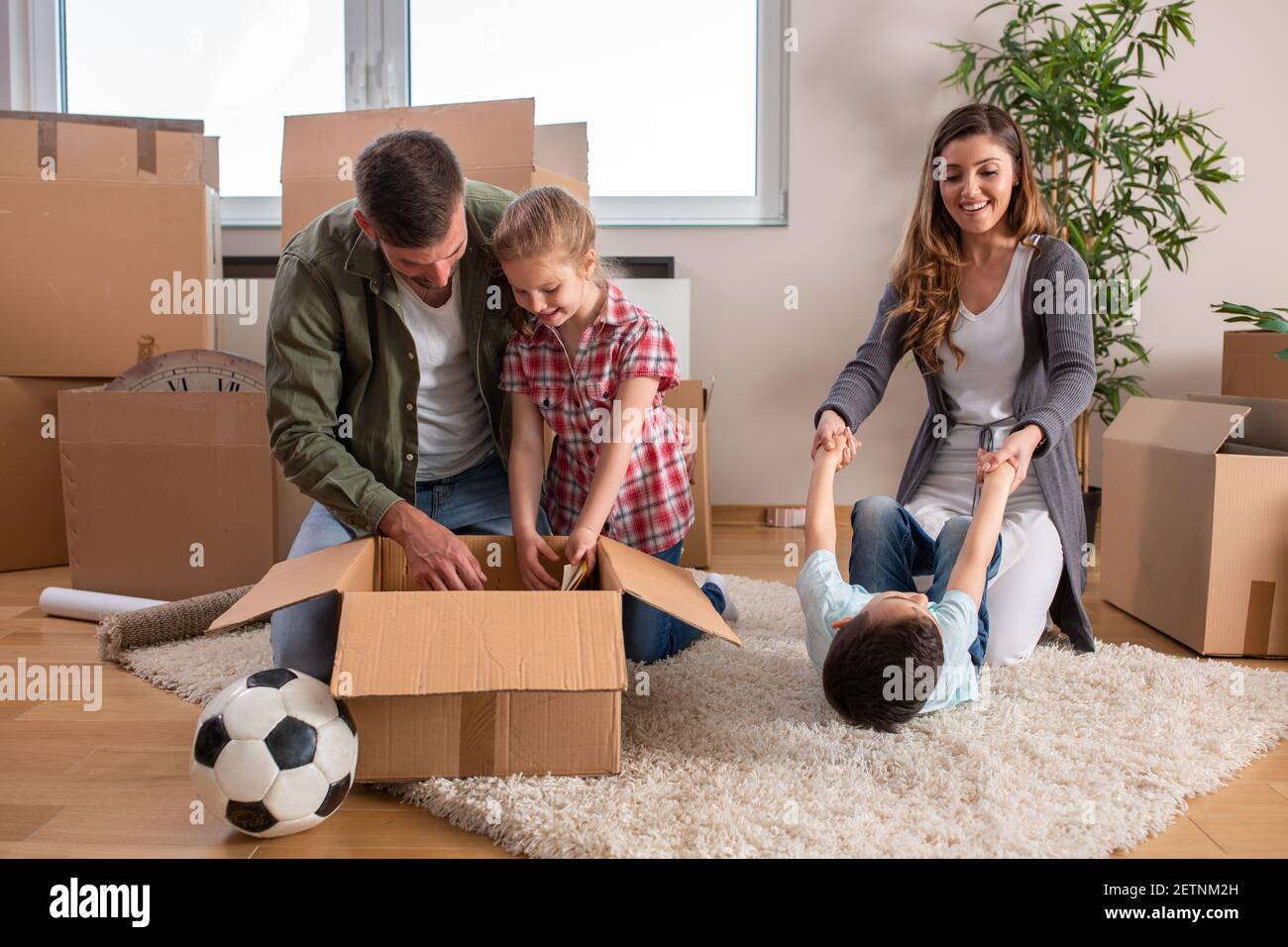 Young couple moving in a new home with their children helping them ...