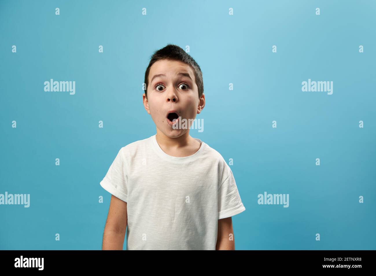 Shocked boy posing with opened mouth expressing surprise on blue ...
