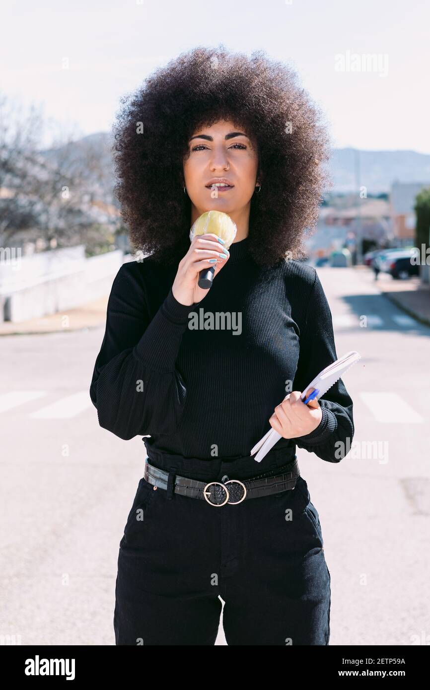 Female television reporter journalist with afro hair reporting on a ...