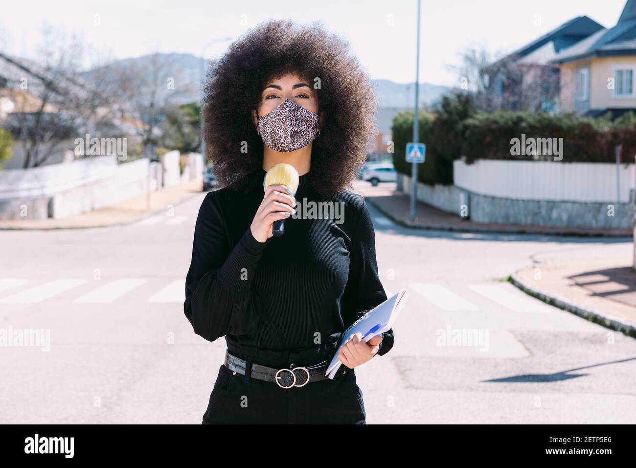 Female television reporter journalist with afro hair, wearing a leopard ...