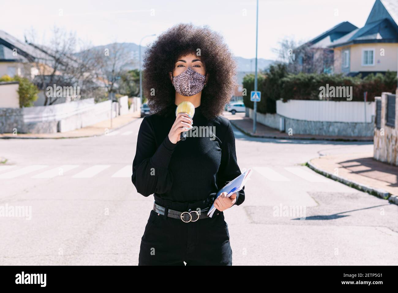 Female television reporter journalist with afro hair, wearing a leopard ...