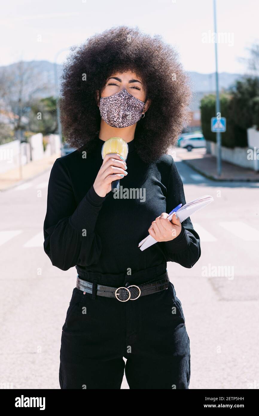 Female television reporter journalist with afro hair, wearing a leopard ...