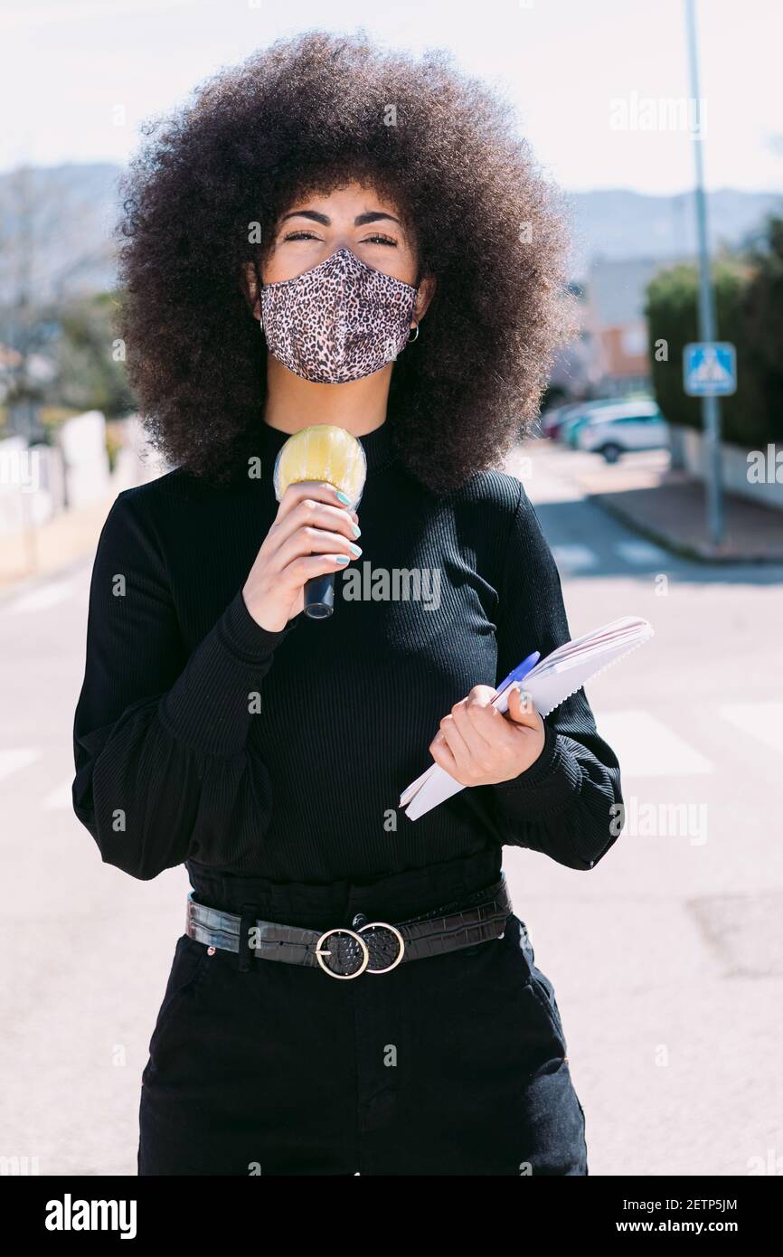 Female television reporter journalist with afro hair, wearing a leopard ...