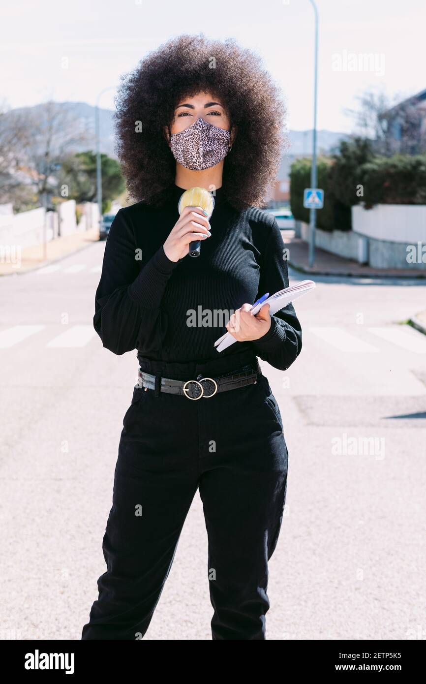 Female television reporter journalist with afro hair, wearing a leopard ...