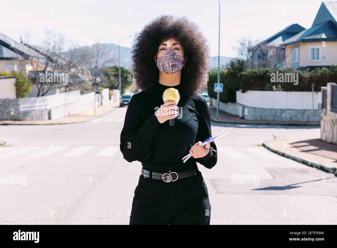 Female television reporter journalist with afro hair, wearing a leopard ...