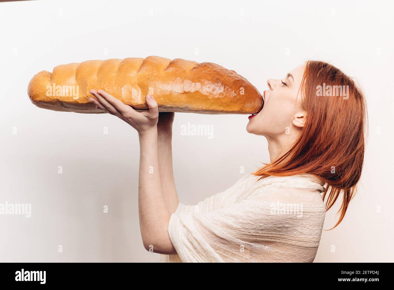 hungry woman eating large loaf of bread loaf side view light background ...