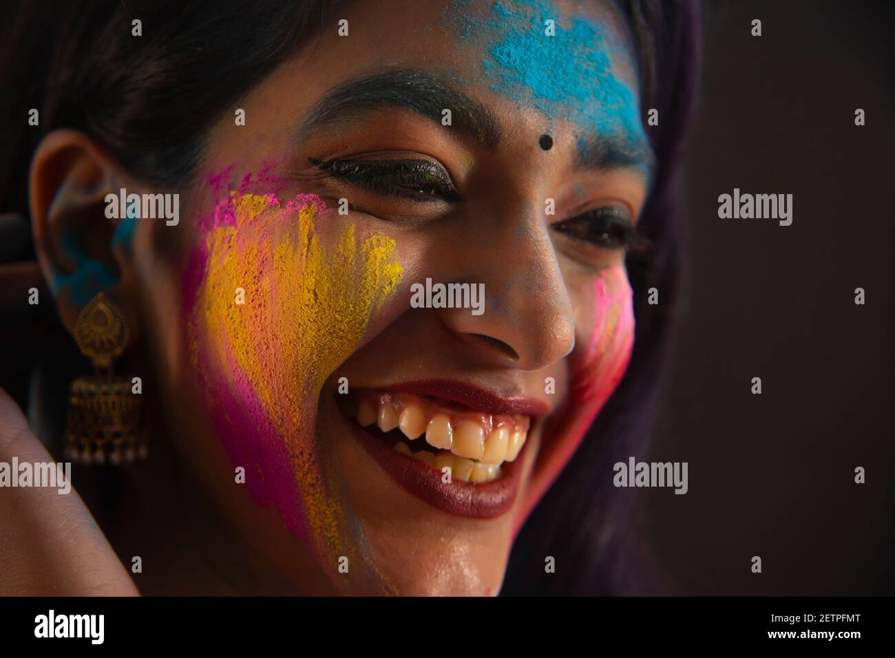 A YOUNG WOMAN WITH GULAL ON HER FACE LOOKING AWAY AND LAUGHING Stock ...