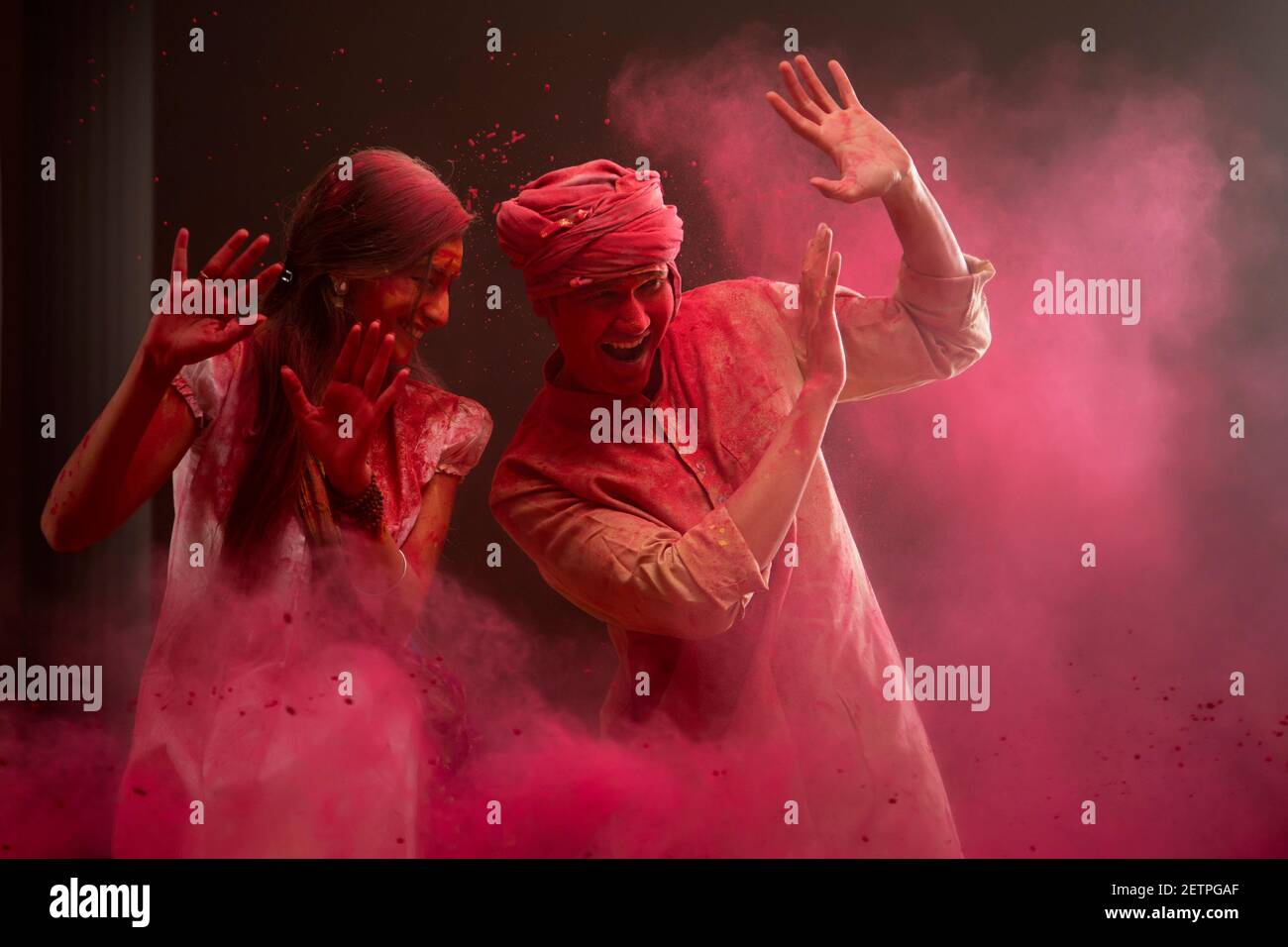A HAPPY YOUNG WOMAN AND MAN RAISING HANDS TO SHIELD THEMSELVES FROM ...