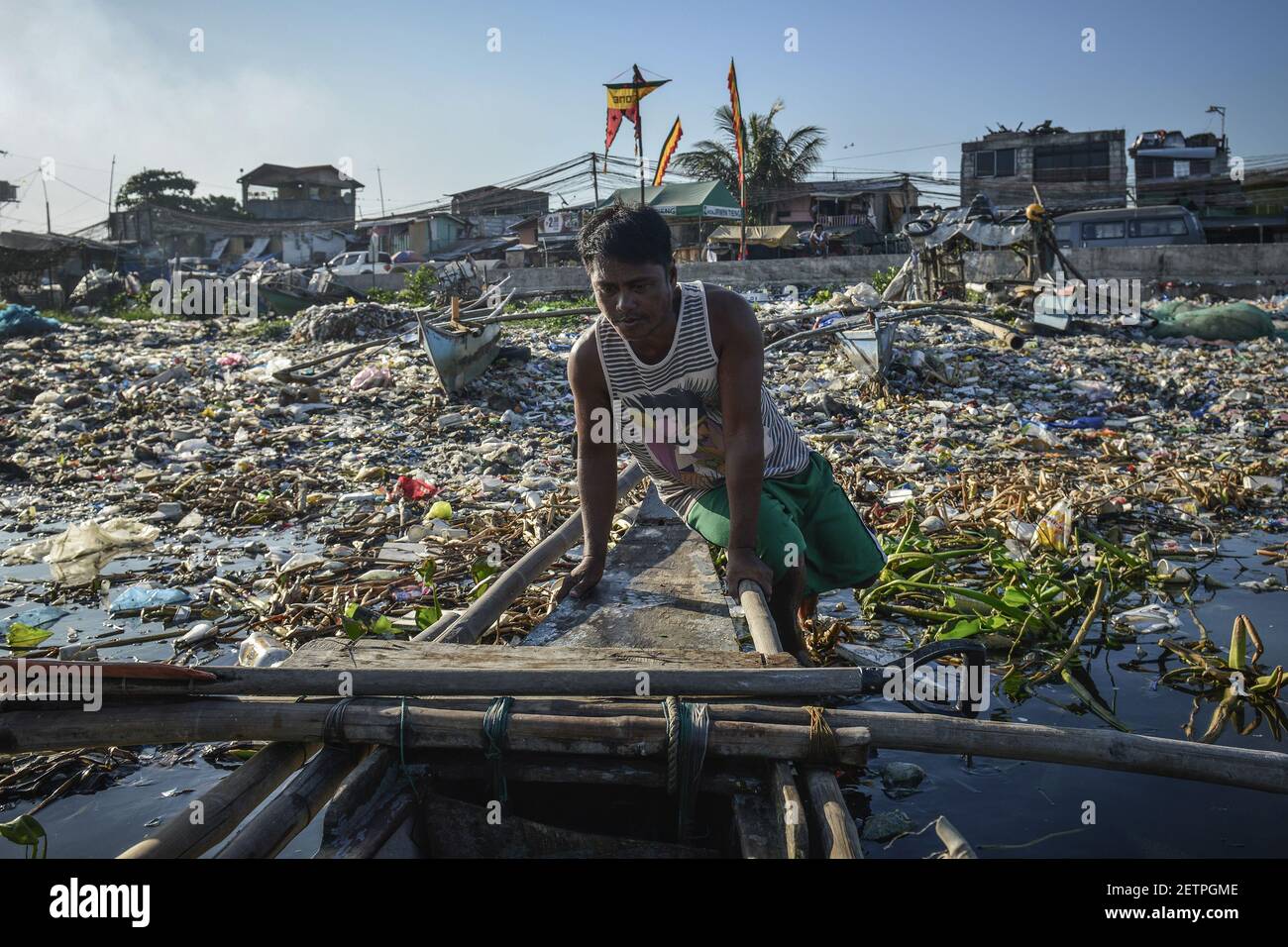 A resident pushes his makeshift boat off the polluted shore of a slum ...