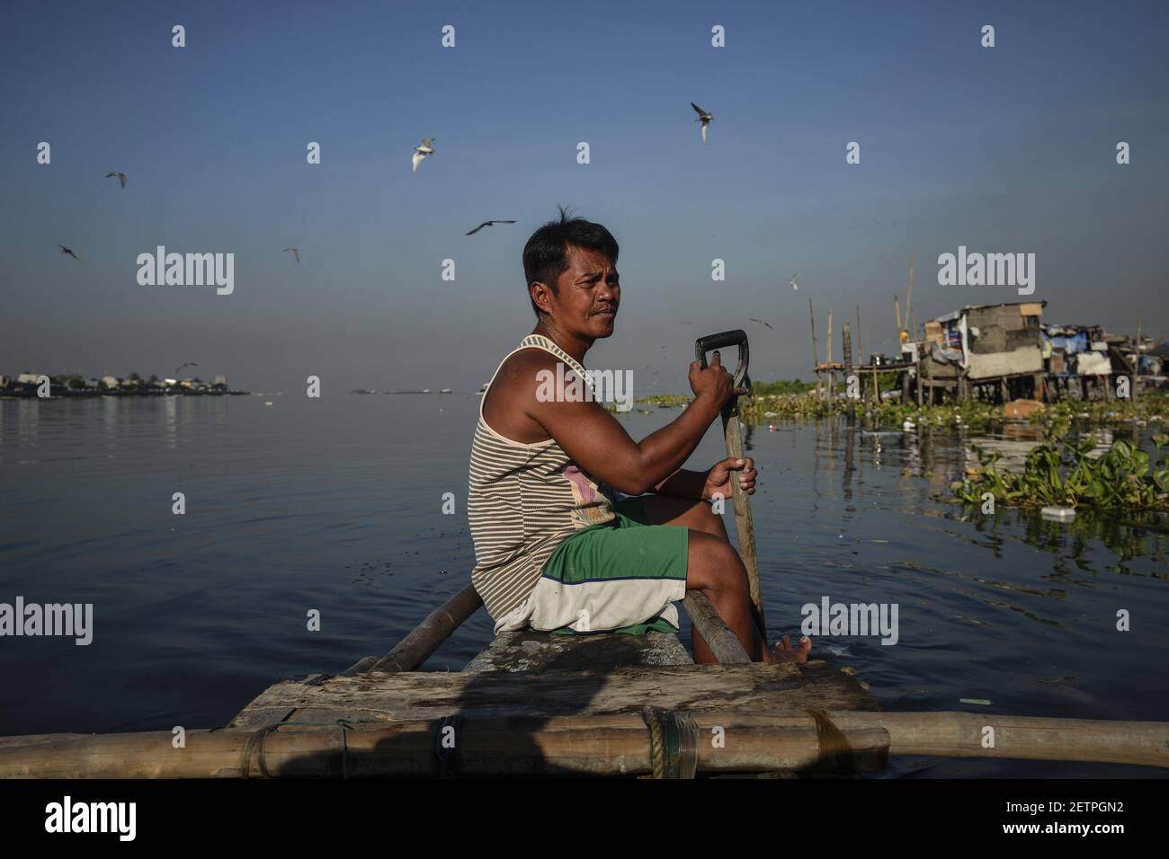 A resident paddles his makeshift boat along a polluted river in Manila ...