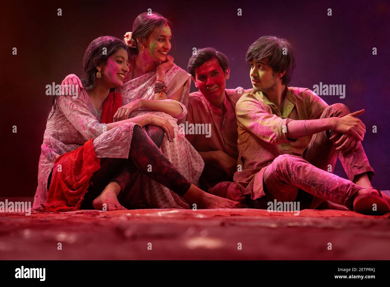 YOUNG MEN AND WOMEN SITTING TOGETHER AND ENJOYING HOLI CELEBRATIONS ...