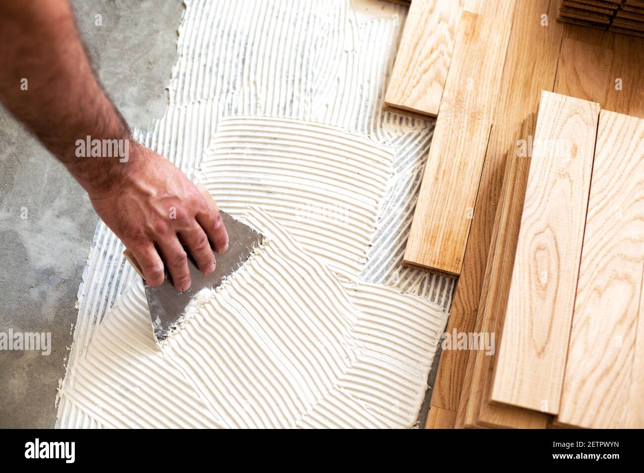 Skilled worker working on subfloor creation for parquet floor assembly ...