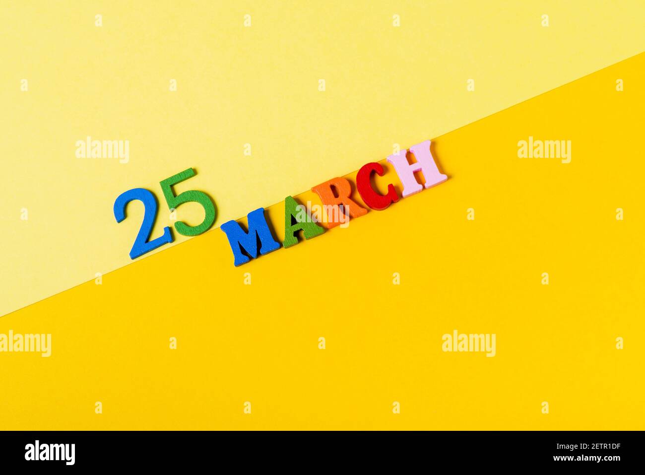 March 25, wooden letters on a yellow, paper background. The concept of ...