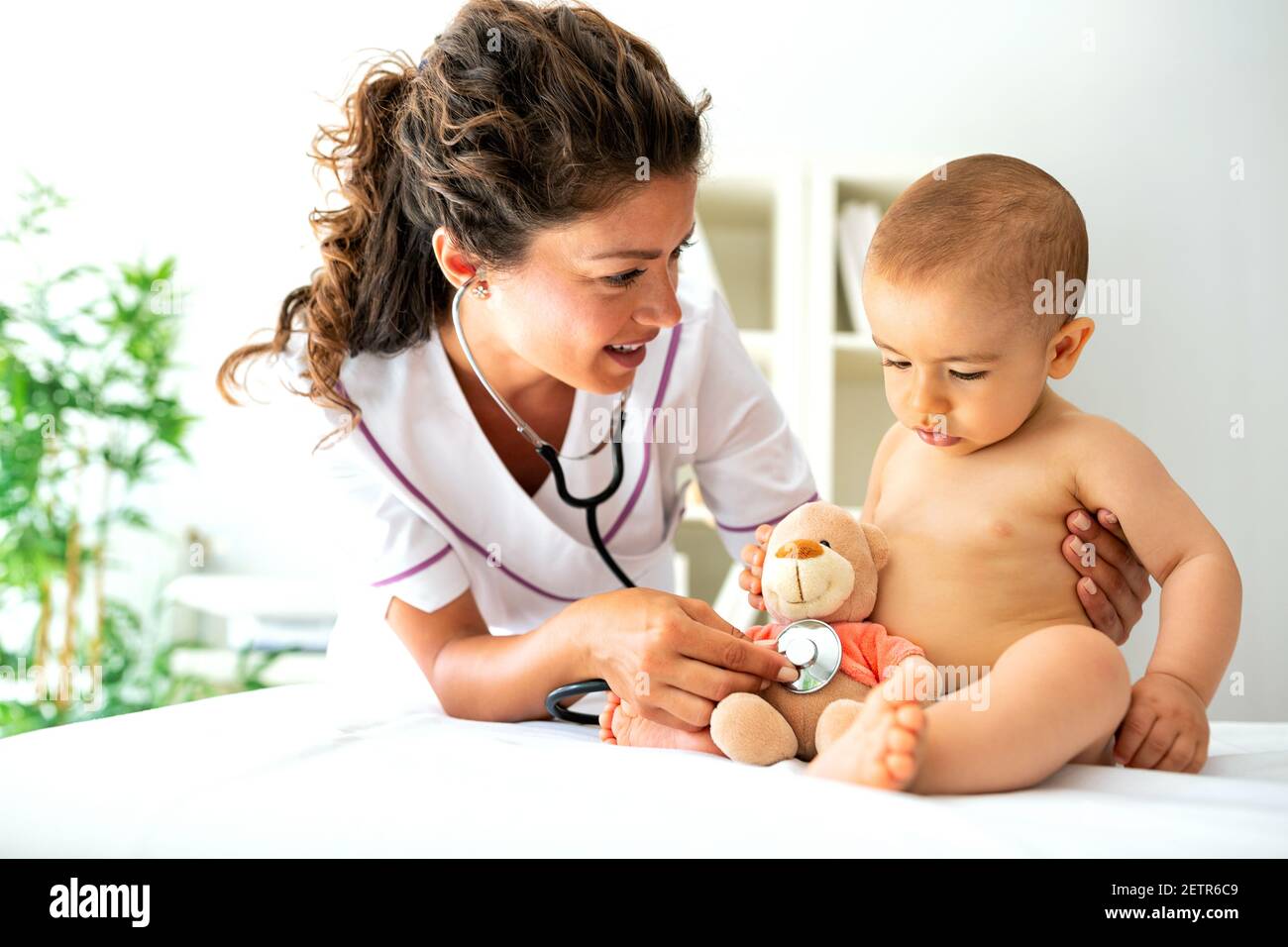 A child specialist showing her baby patient how to examine his teddy ...