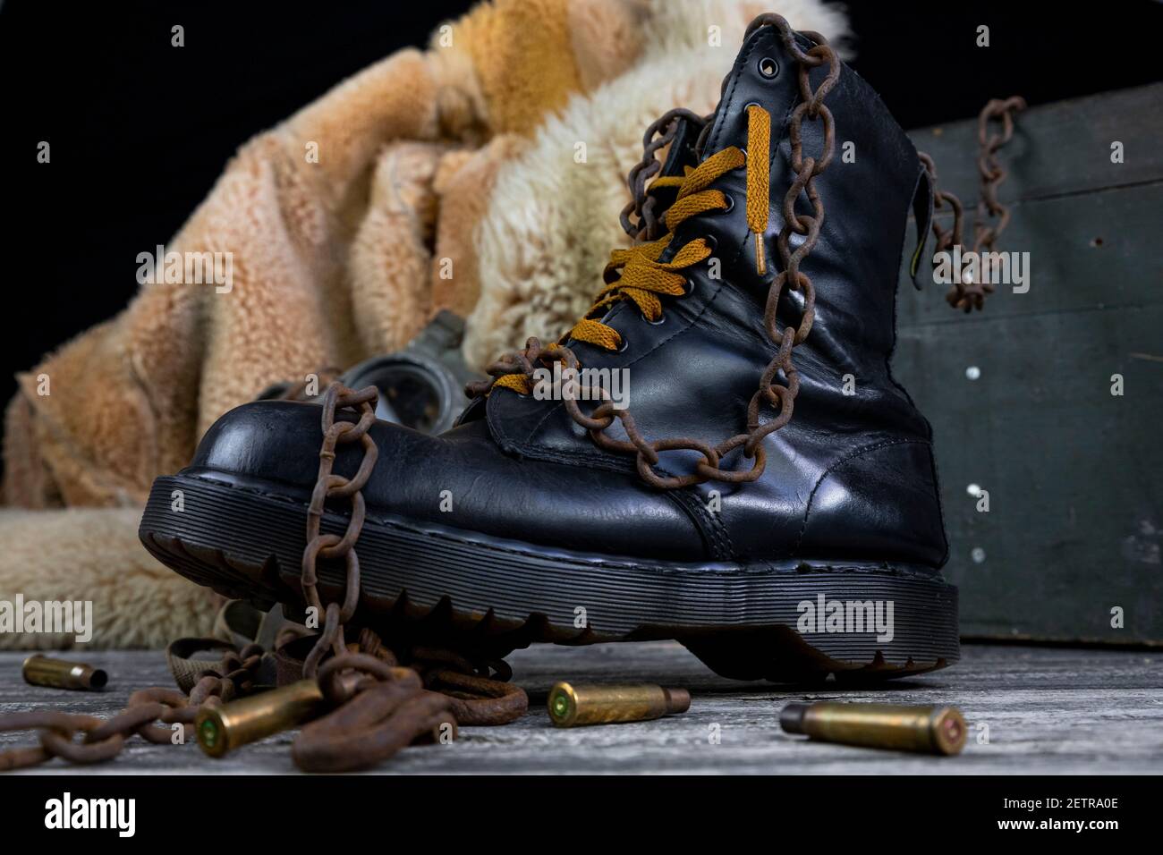 Leather boot with rusted chains and bullet shells with military gas ...