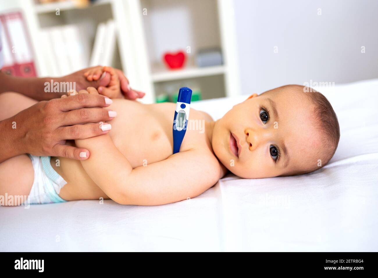 Checking the body temperature of a baby with baby lying down and being ...