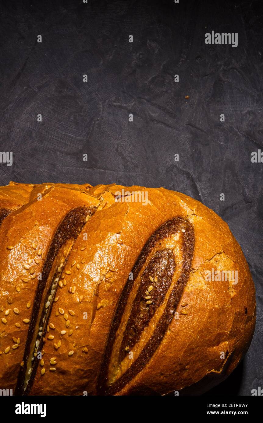 Unusual two-color fresh loaf of bread on a black background, photo in a ...