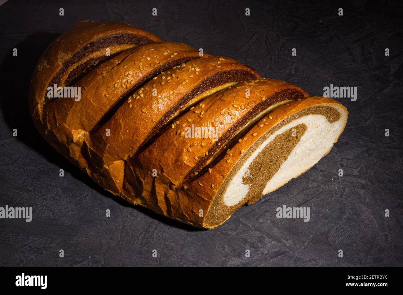 Unusual two-color fresh loaf of bread on a black background, photo in a ...