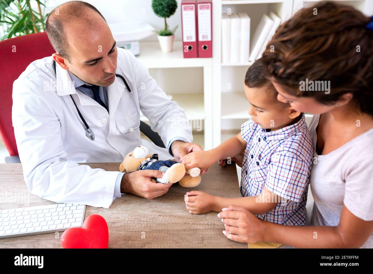 A cute boy explaining about his teddy bear and telling his doctor about ...