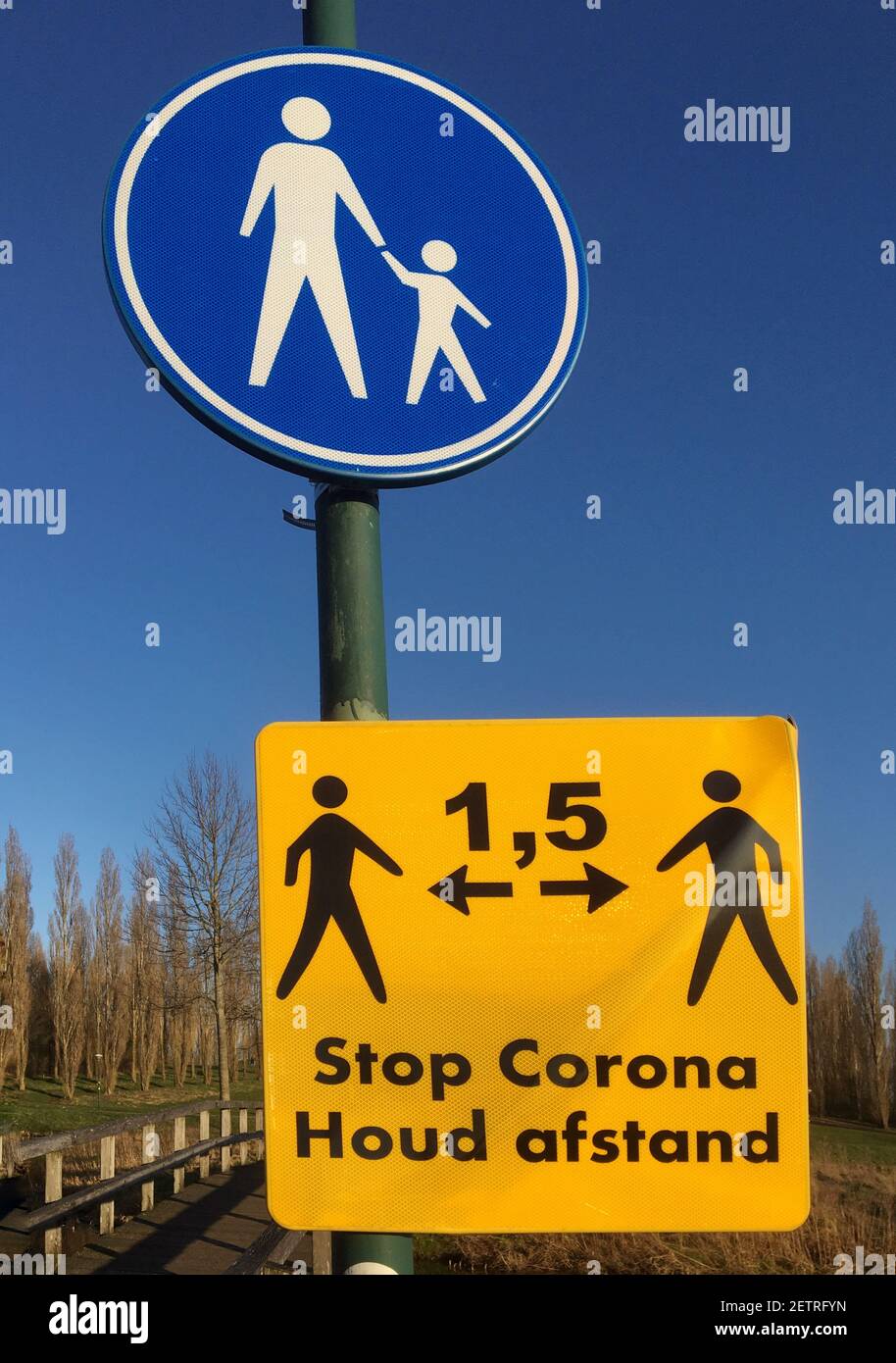 Traffic sign for a footh path, with a corona warning sign underneath ...