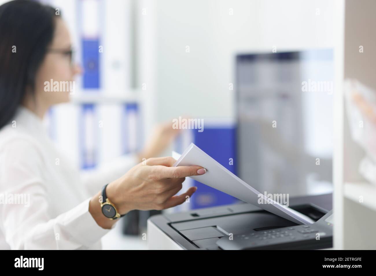 Young woman pulling paper out of printer closeup Stock Photo - Alamy