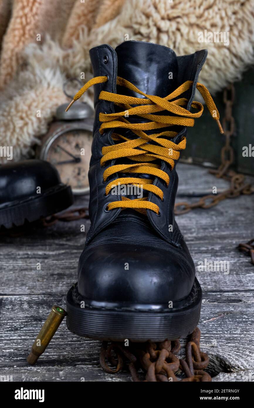 Leather boot with rusted chains and bullet shells with military gas ...