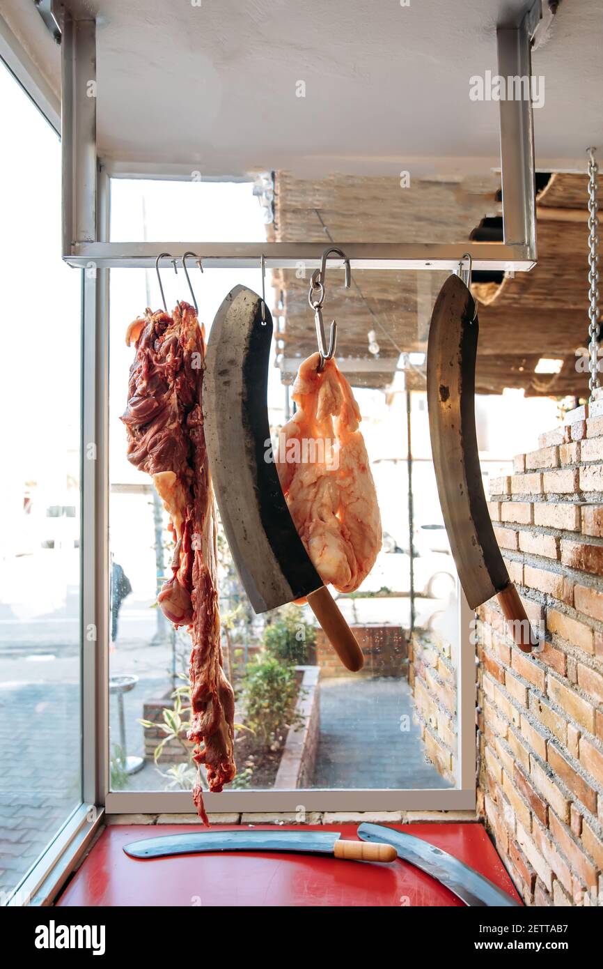 Meat hanged in butcher market with knives Stock Photo - Alamy