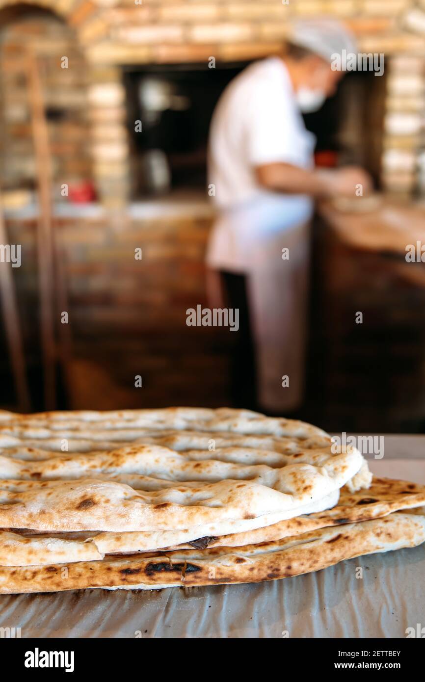Traditional Turkish ramadan pita or pide bread with baker in bakery ...