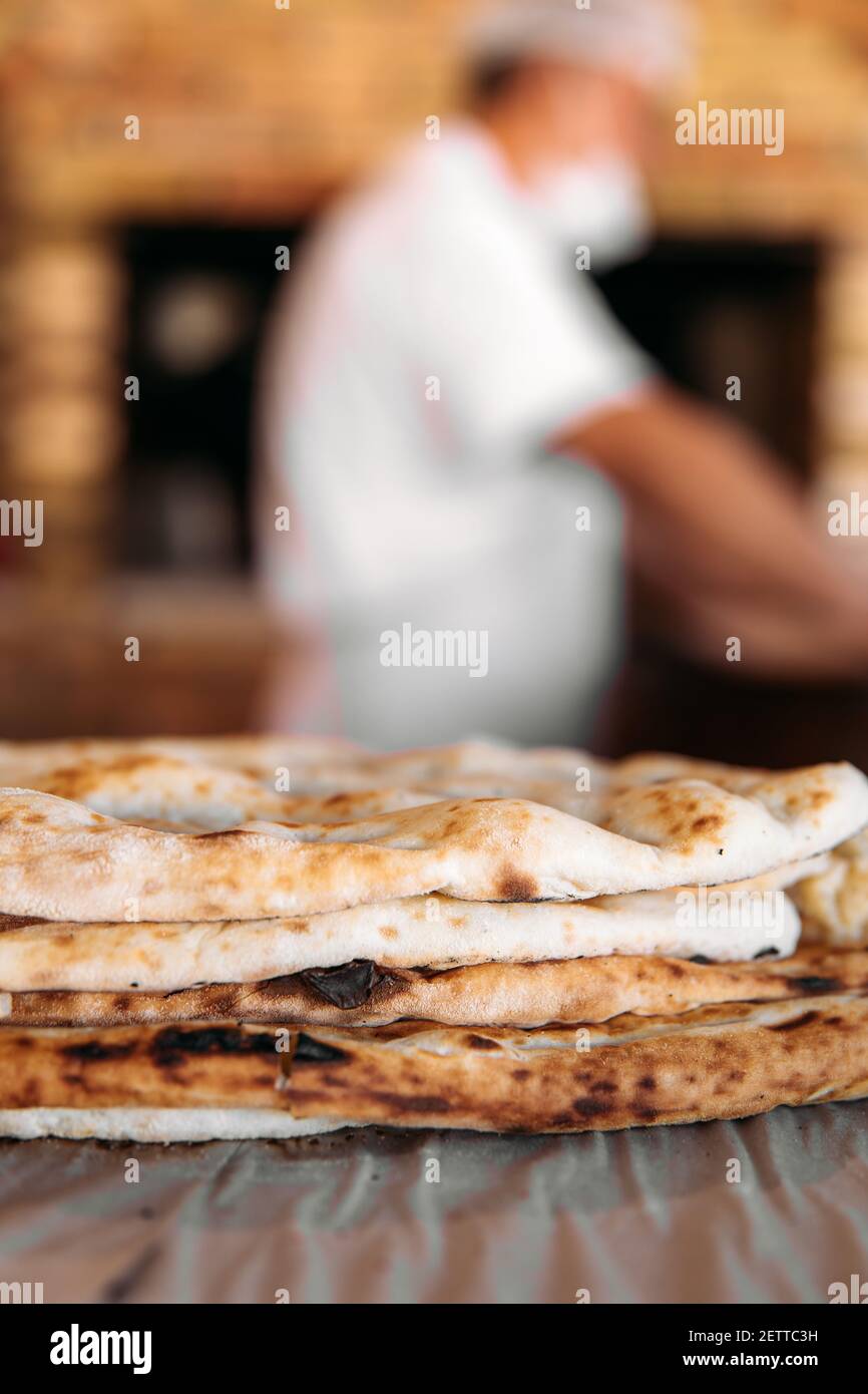 Traditional Turkish ramadan pita or pide bread with baker in bakery ...