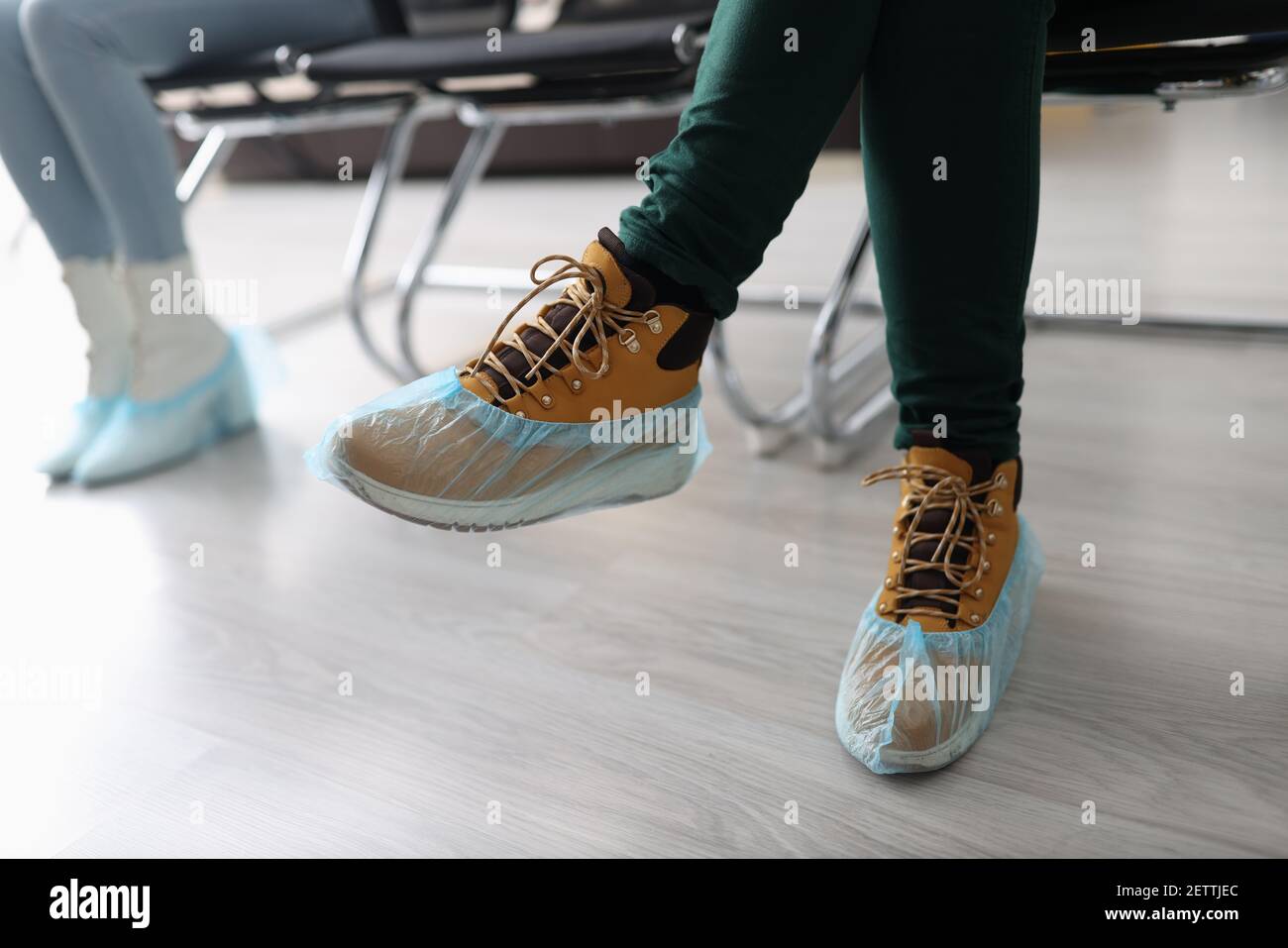 Women sitting in line with shoe covers on their feet closeup Stock ...