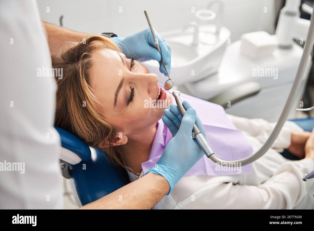 Doctor taking care of calm lady teeth with drill machine Stock Photo ...