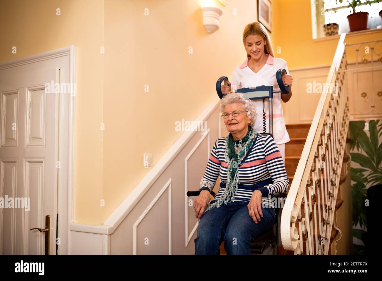 Smiling old lady, happy while nurse helps her to climb to the stairs at ...