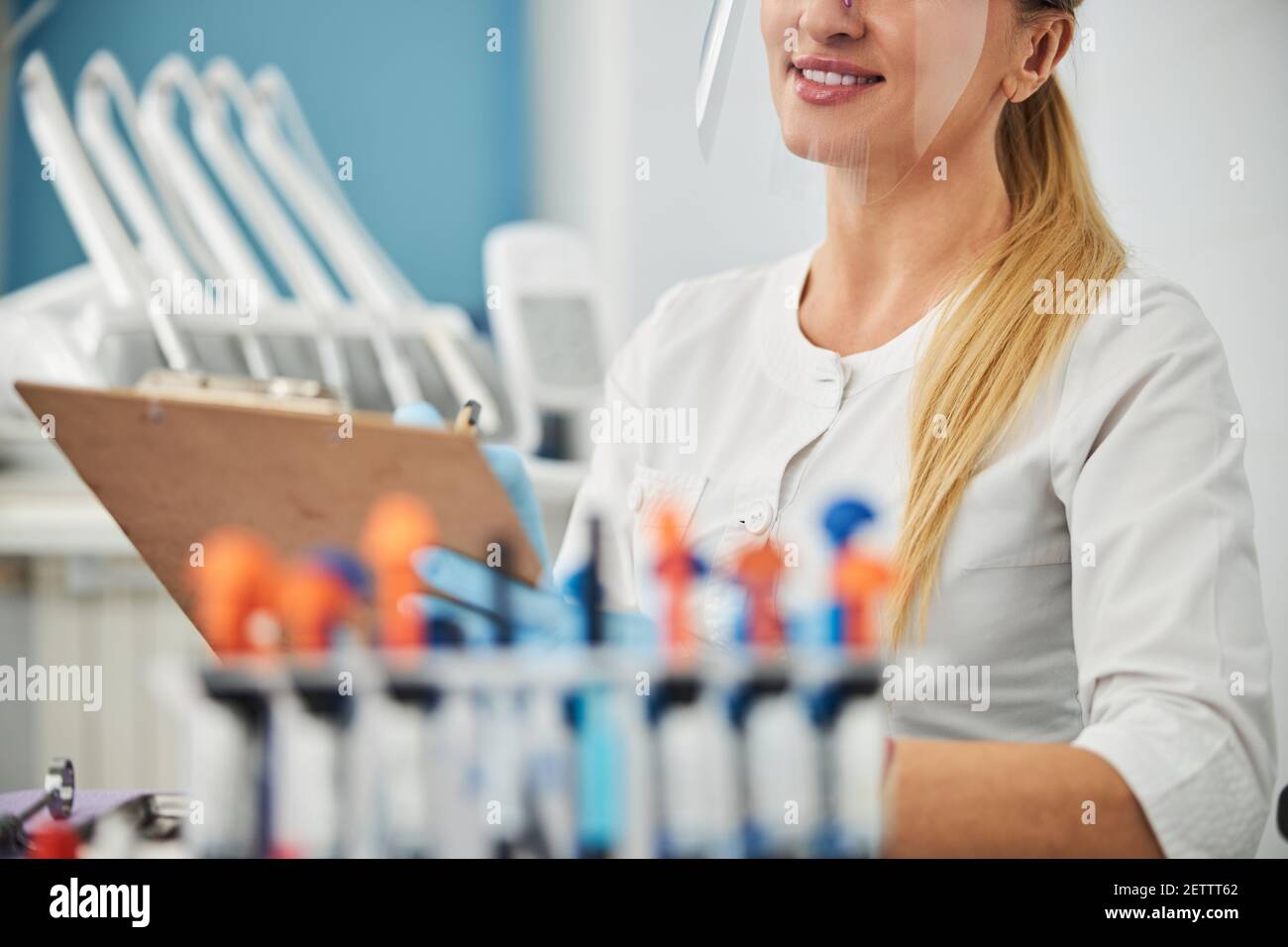 Joyful lady taking notes while holding clipboard Stock Photo - Alamy