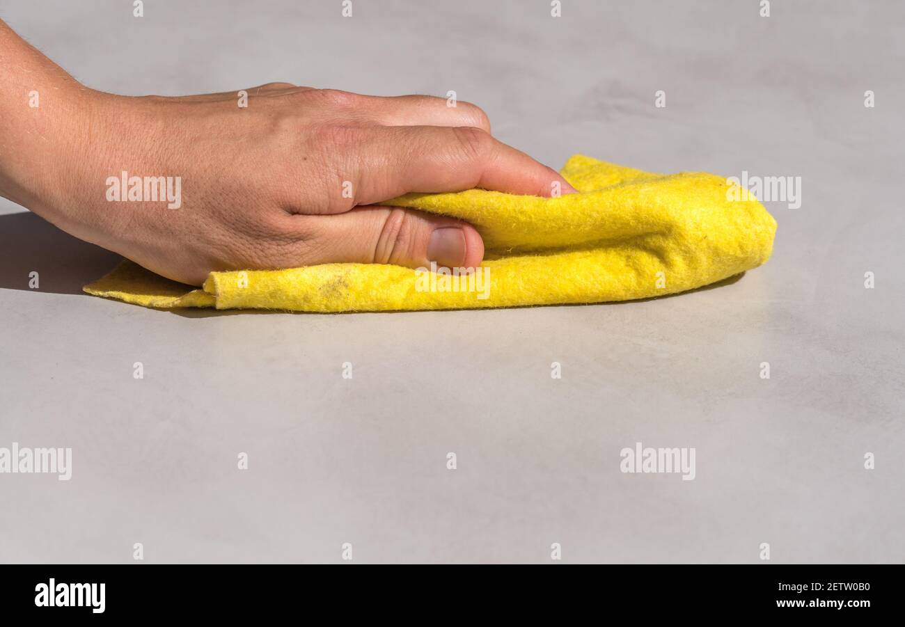 woman's hand cleaning spilled water on a cement floor with a yellow ...