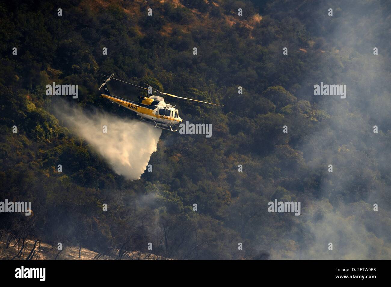 A helicopter makes a water drop on a wildfire in Los Angeles ...