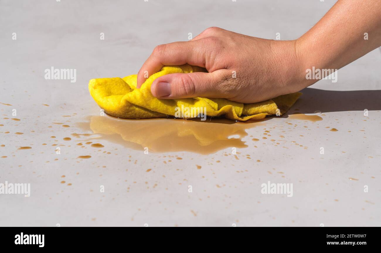 woman's hand cleaning spilled water on a cement floor with a yellow ...