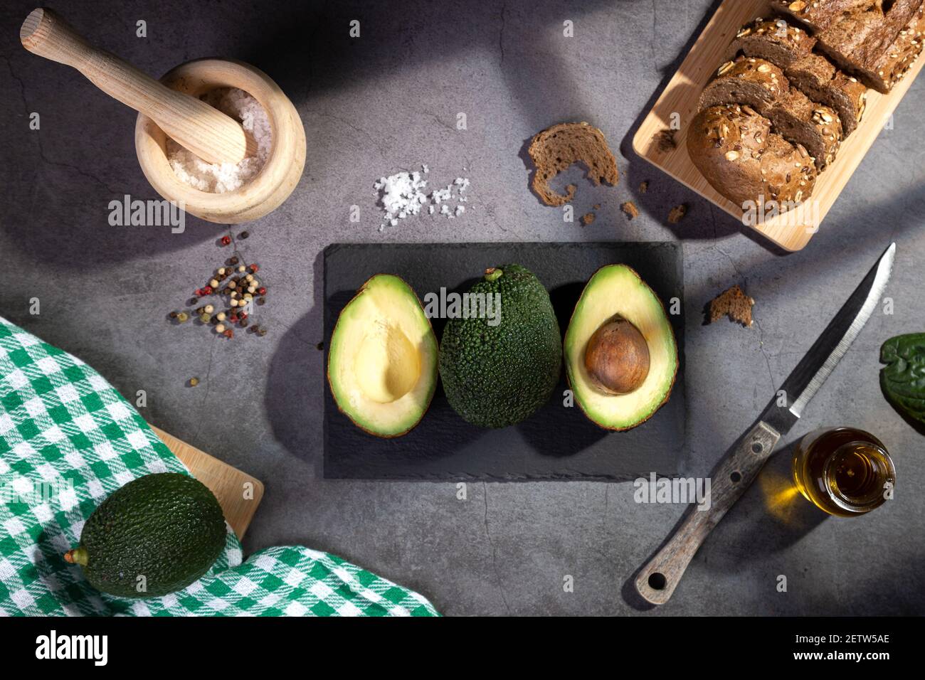 Flat lay composition with avocados on dark table with window shades ...