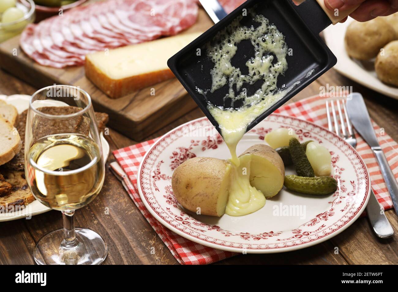 Raclette cheese melted by raclette pan is putting on freshly boiled ...