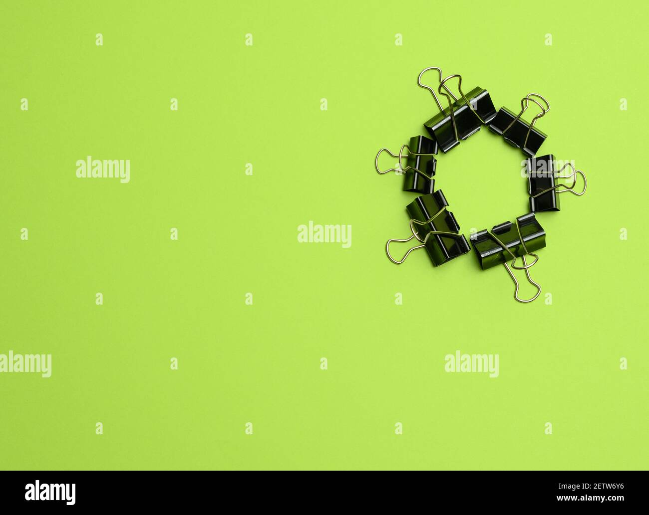stack of black metal stationery clips on a green background, top view ...